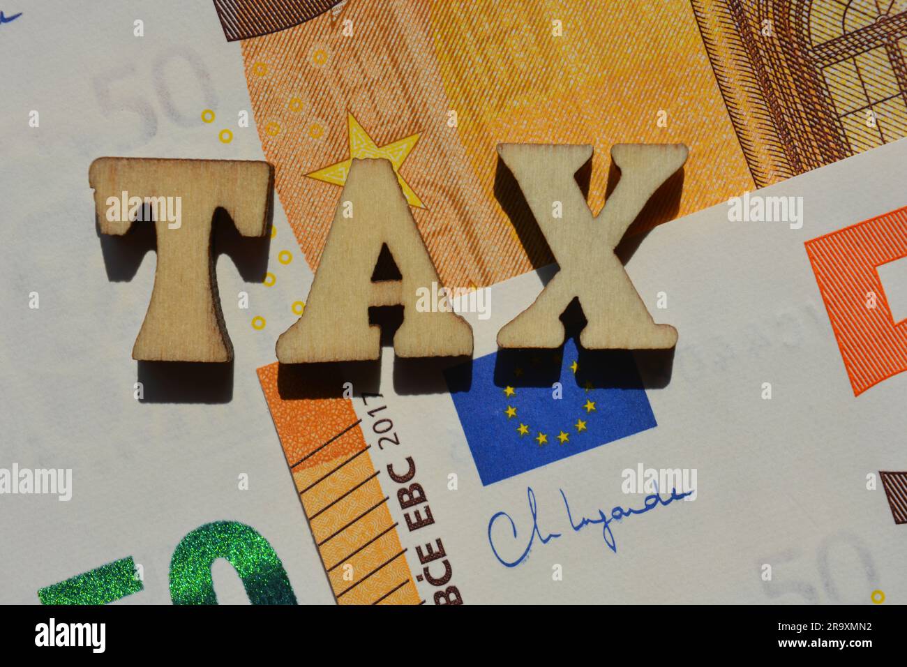 Tax, word in wooden alphabet letters isolated on background of euro ...