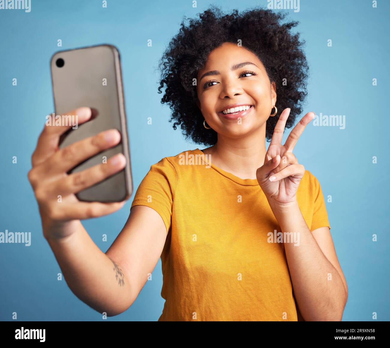 Selfie, peace sign and young woman isolated on blue background for ...