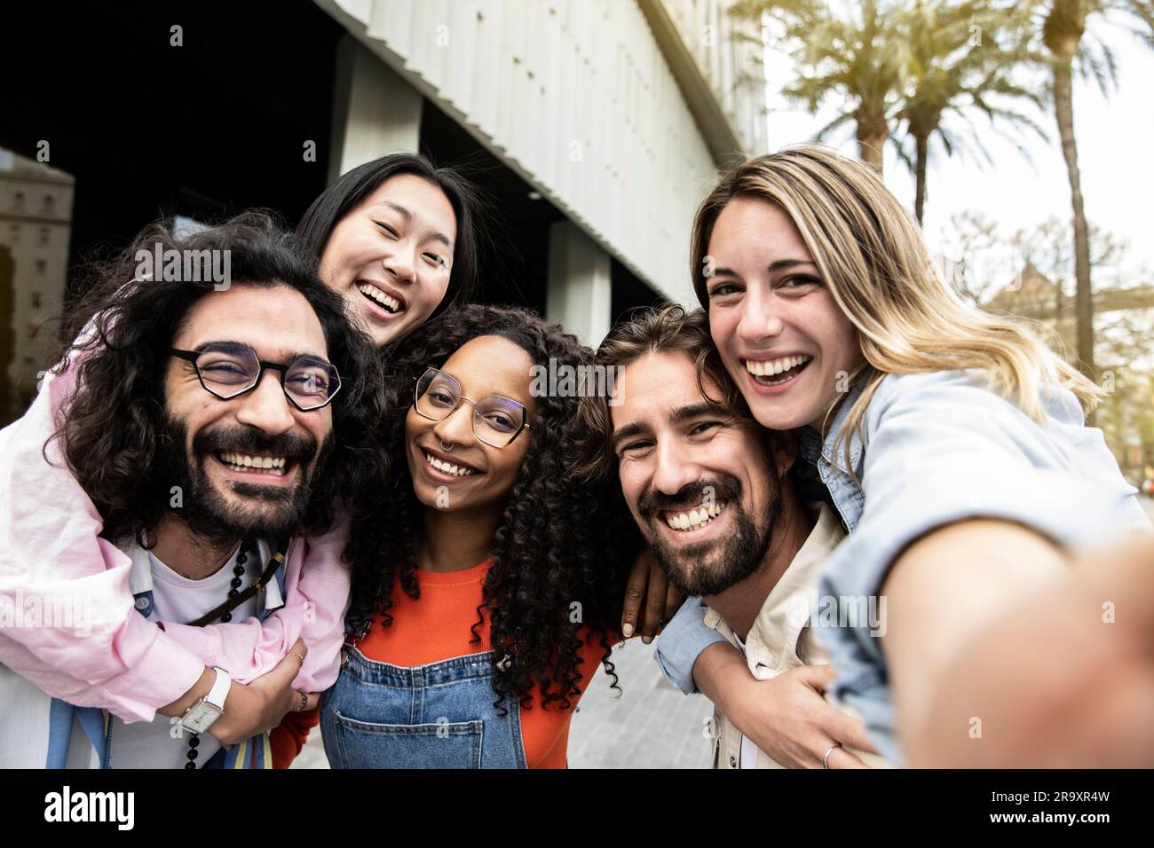 Diverse group of friends laughing hugging each other and taking a ...