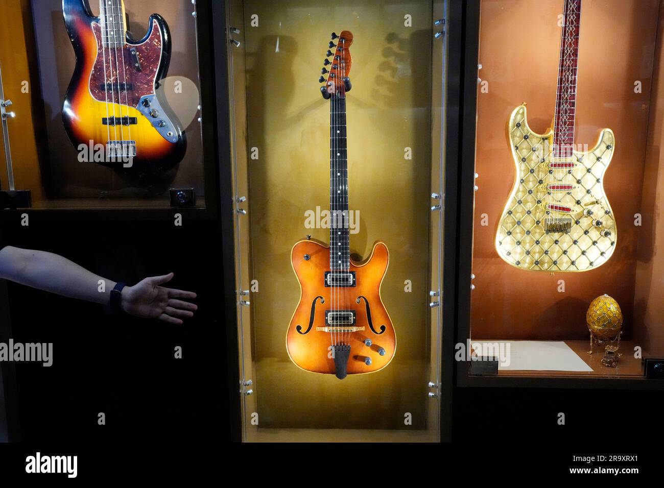 A staff guides Fender guitars on display during the press preview of ...