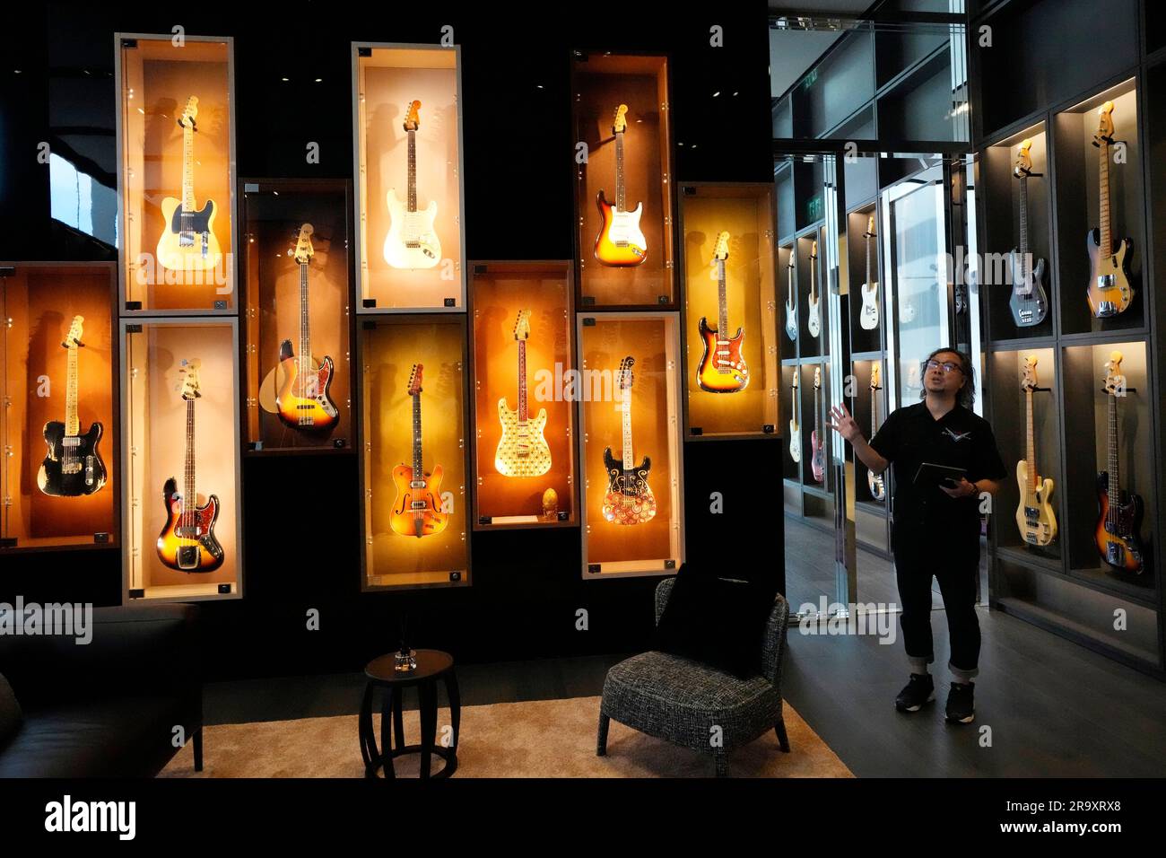 A staff guides Fender guitars on display during the press preview of ...