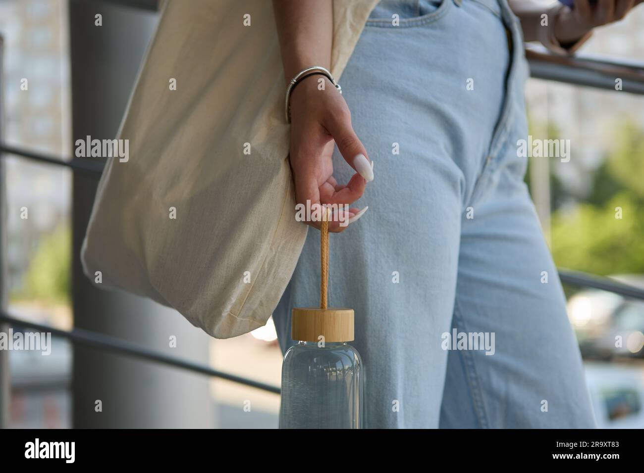Young girl holding a glass water bottle on a walk. Responsible young ...