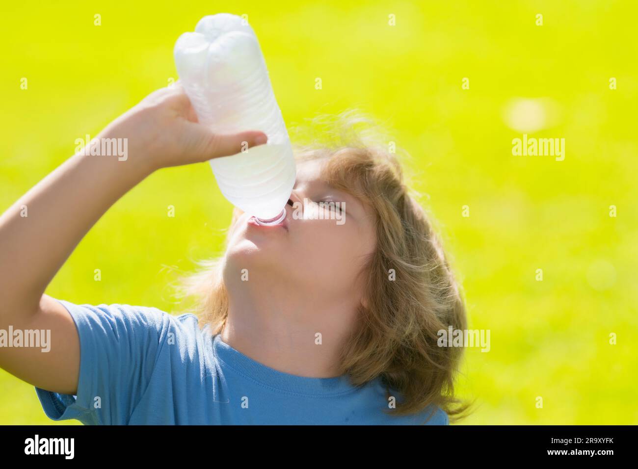 Little kid drinking a fresh bottle of water. Thirsty child holding ...