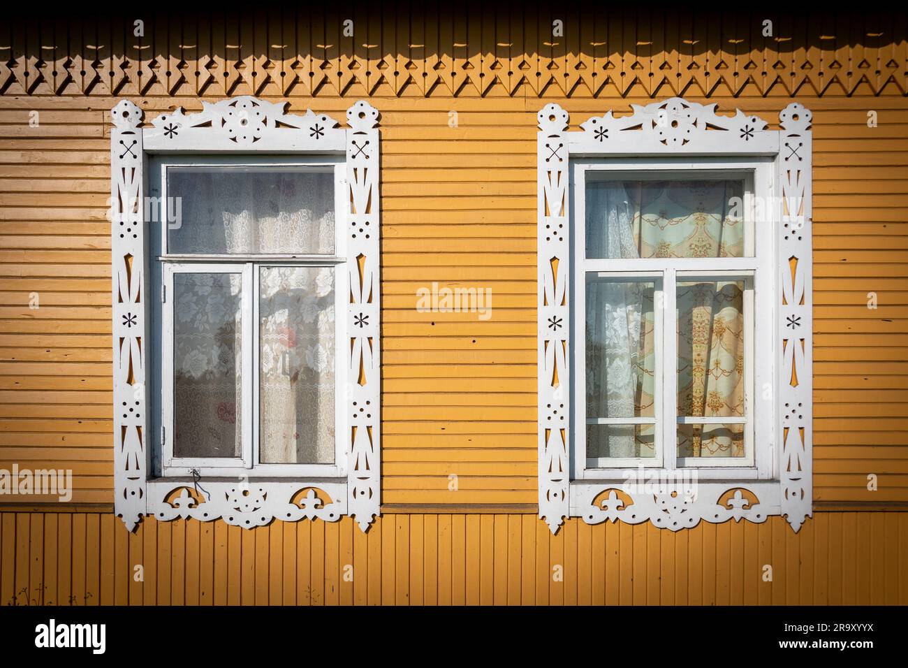 Two windows framed with carved wooden jambs decorated with traditional ...