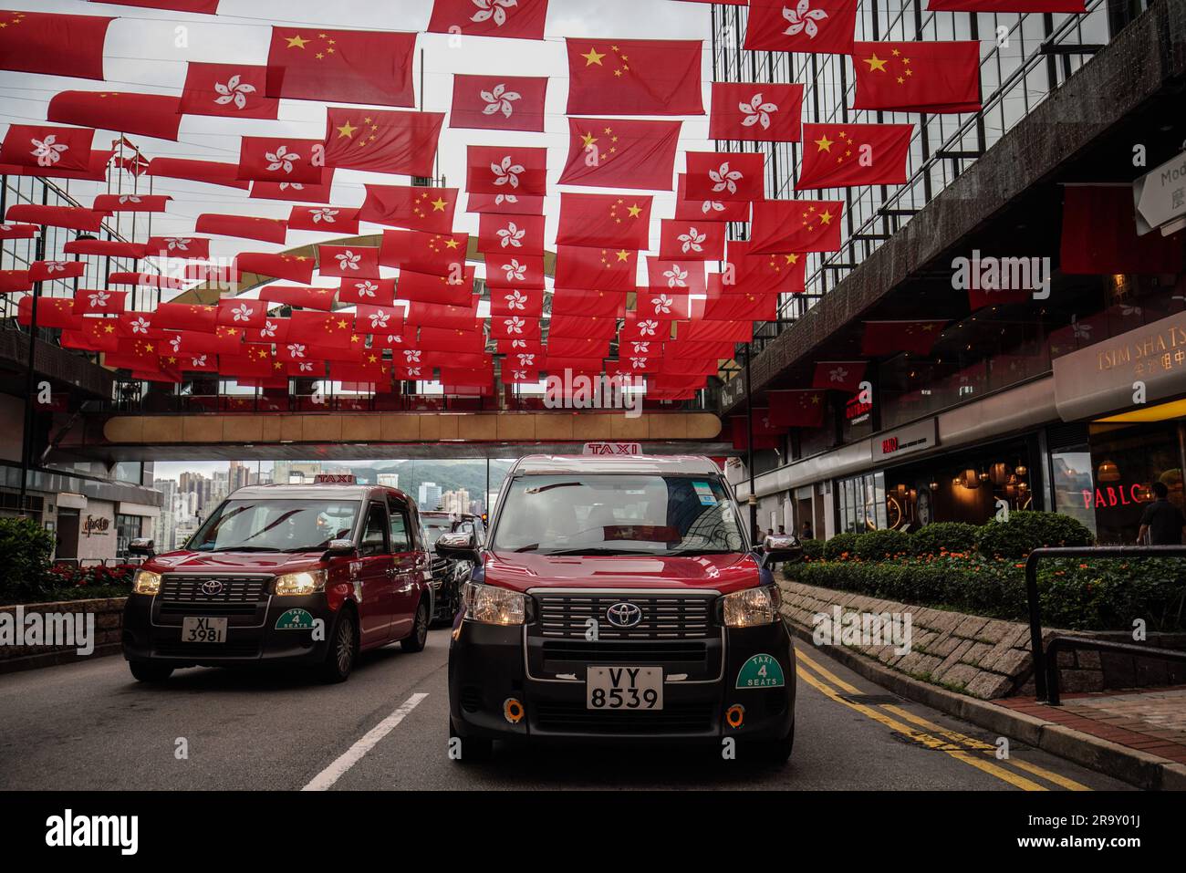 Cars are driven on the street and flags of China and Hong Kong hang on ...