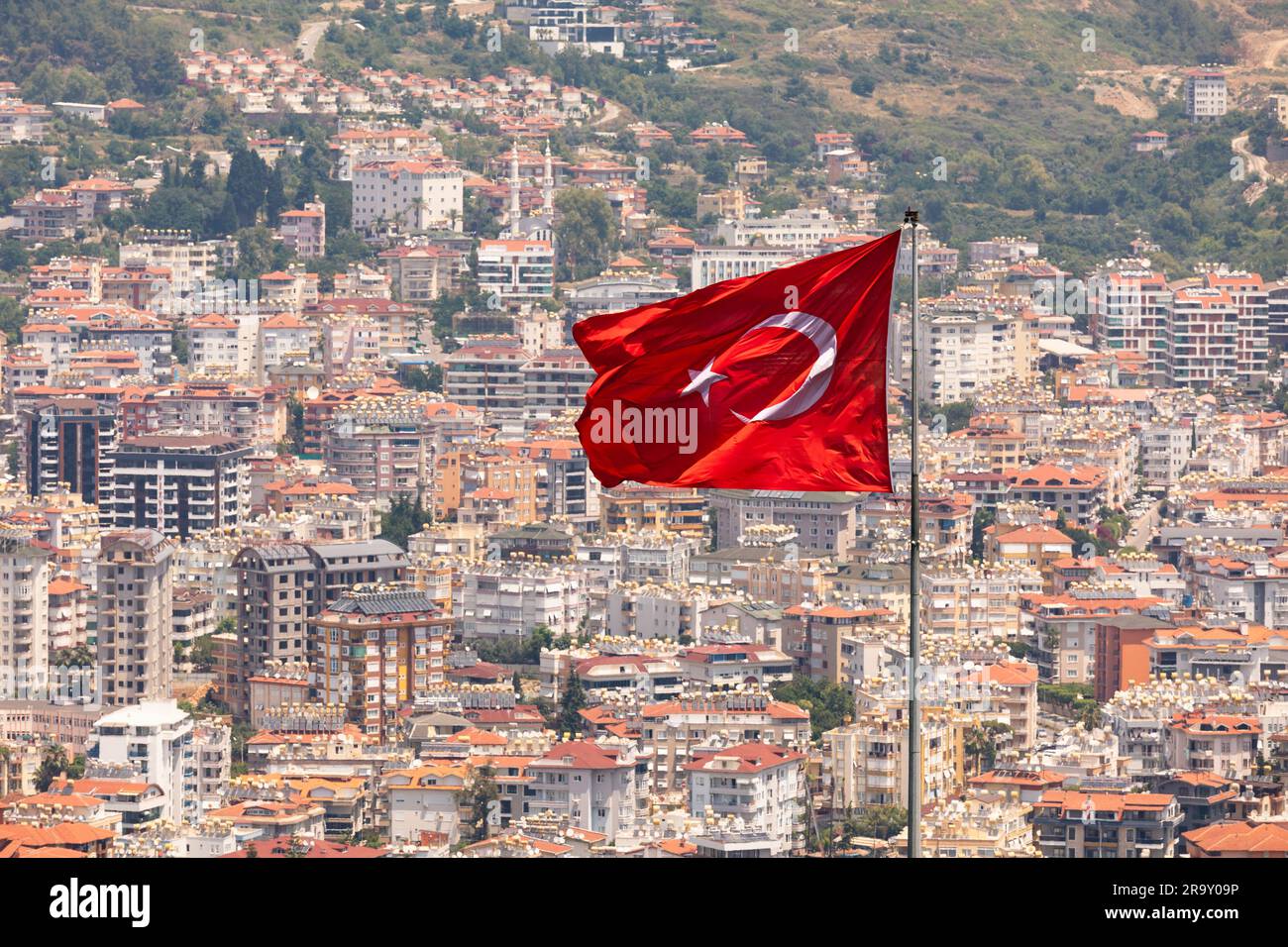 Waving Turkish flag on a flagpole with urban development in background ...