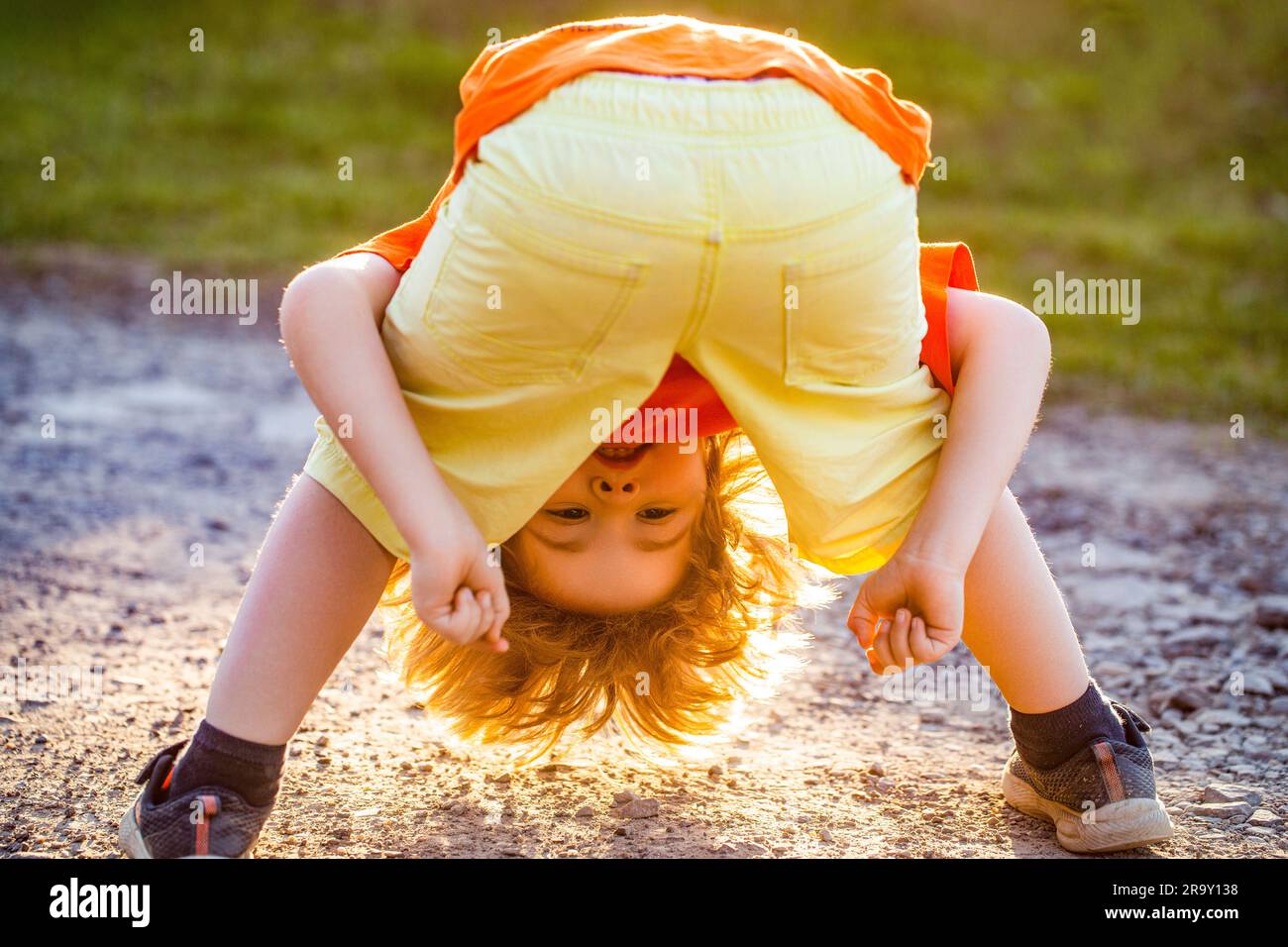 Happy cute child standing upside down. Playing fools kid. Young man ...