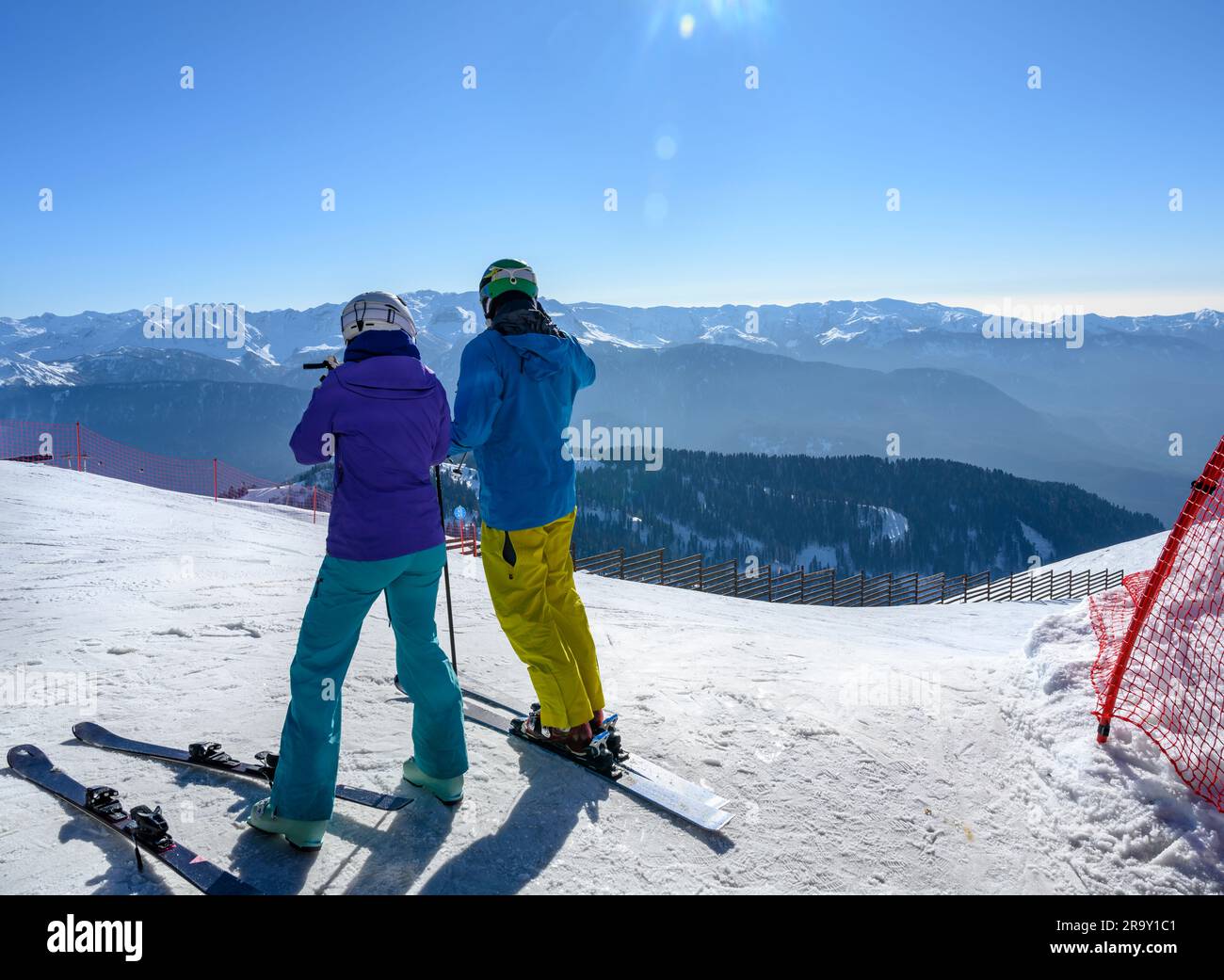 Girls skiing in the bright sun before descending from a steep mountain ...