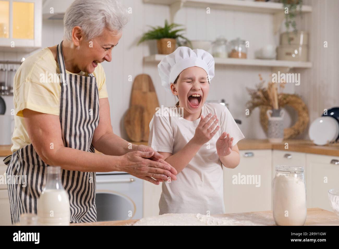 Happy family in kitchen. Grandmother and granddaughter child cook in ...