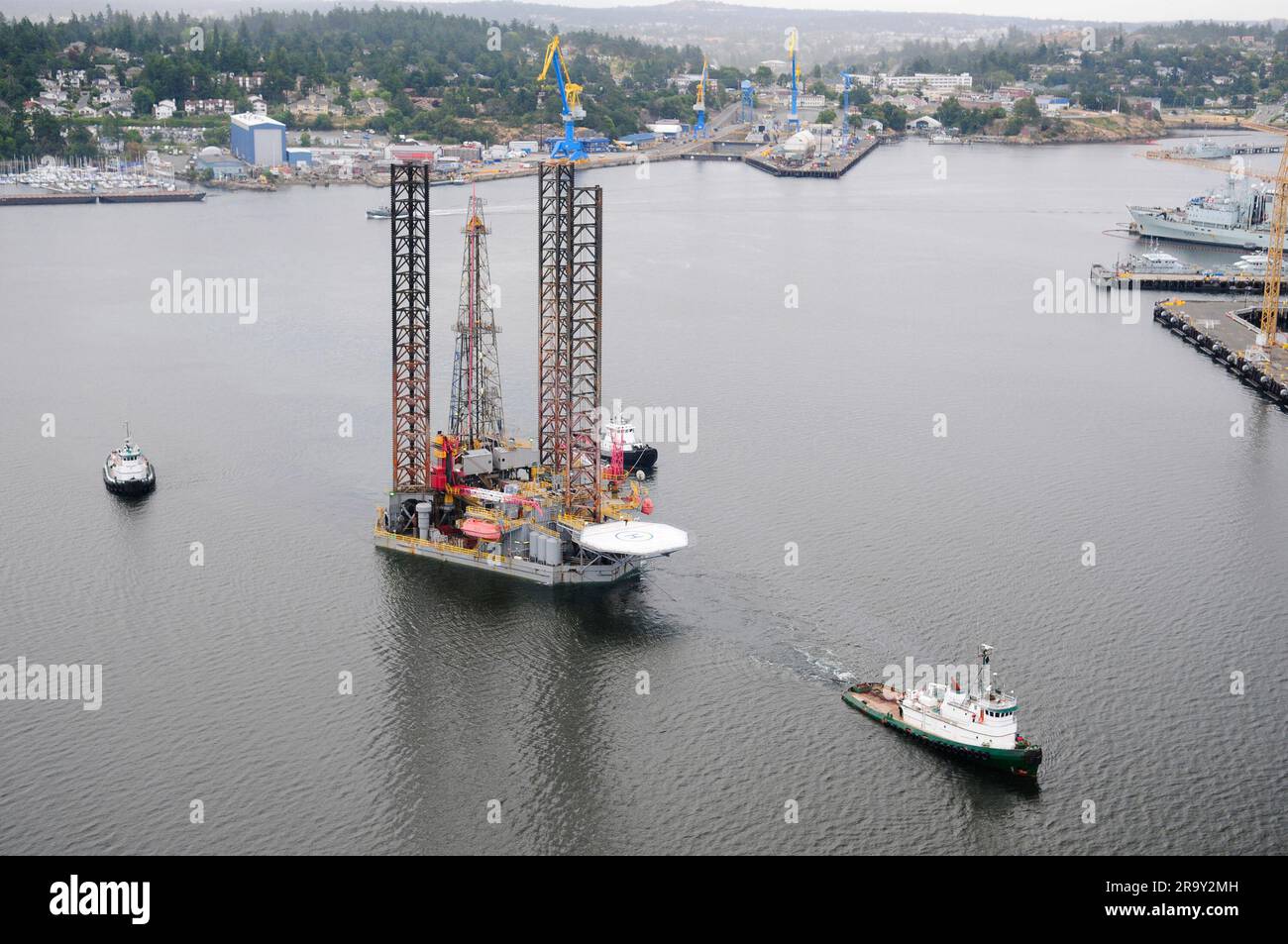 Aerial image of an oil drilling rig being towed out of port by three ...