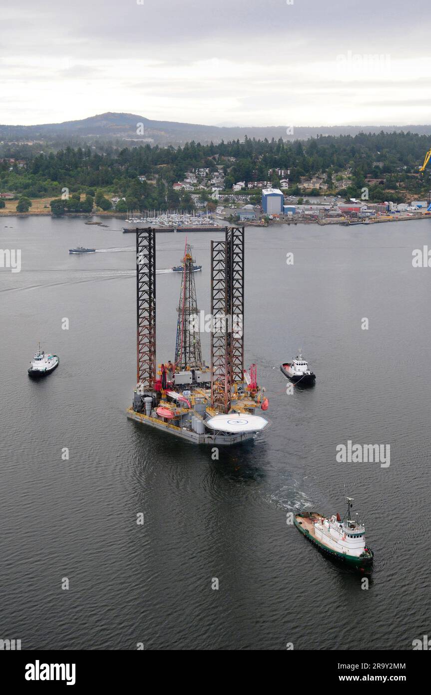 Aerial image of an oil drilling rig being towed out of port by three ...