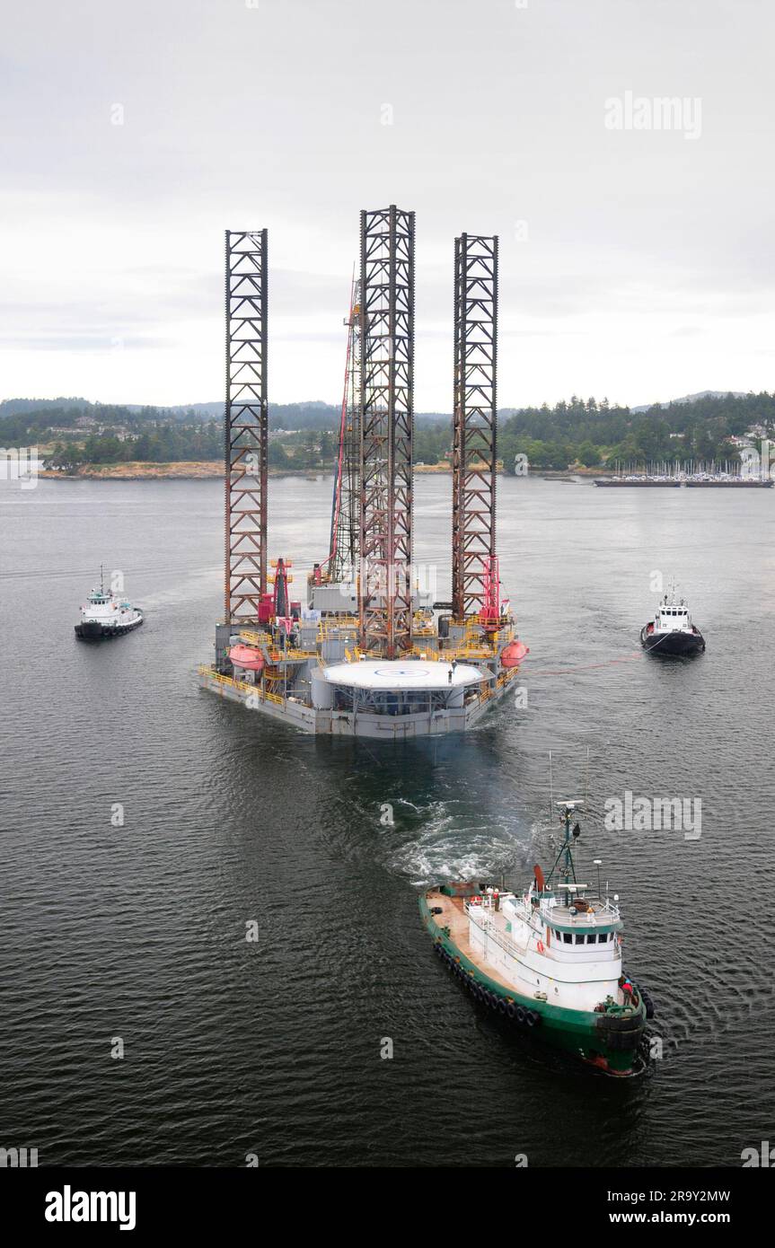 Aerial image of an oil drilling rig being towed out of port by three ...