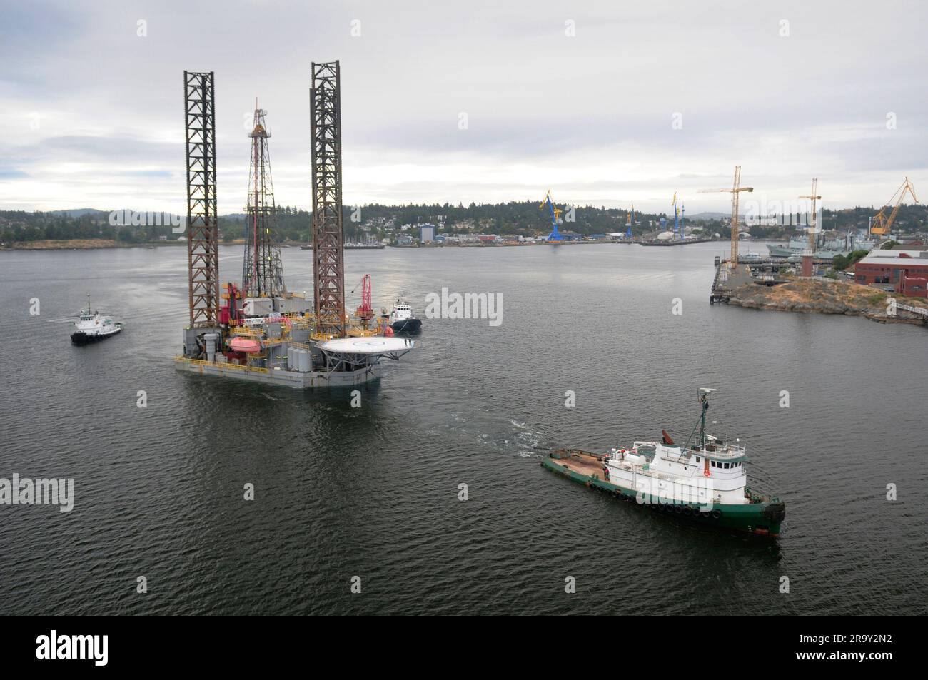 Aerial image of an oil drilling rig being towed out of port by three ...