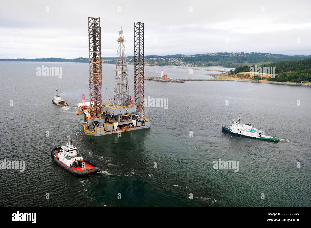 Aerial image of an oil drilling rig being towed out of port by three ...