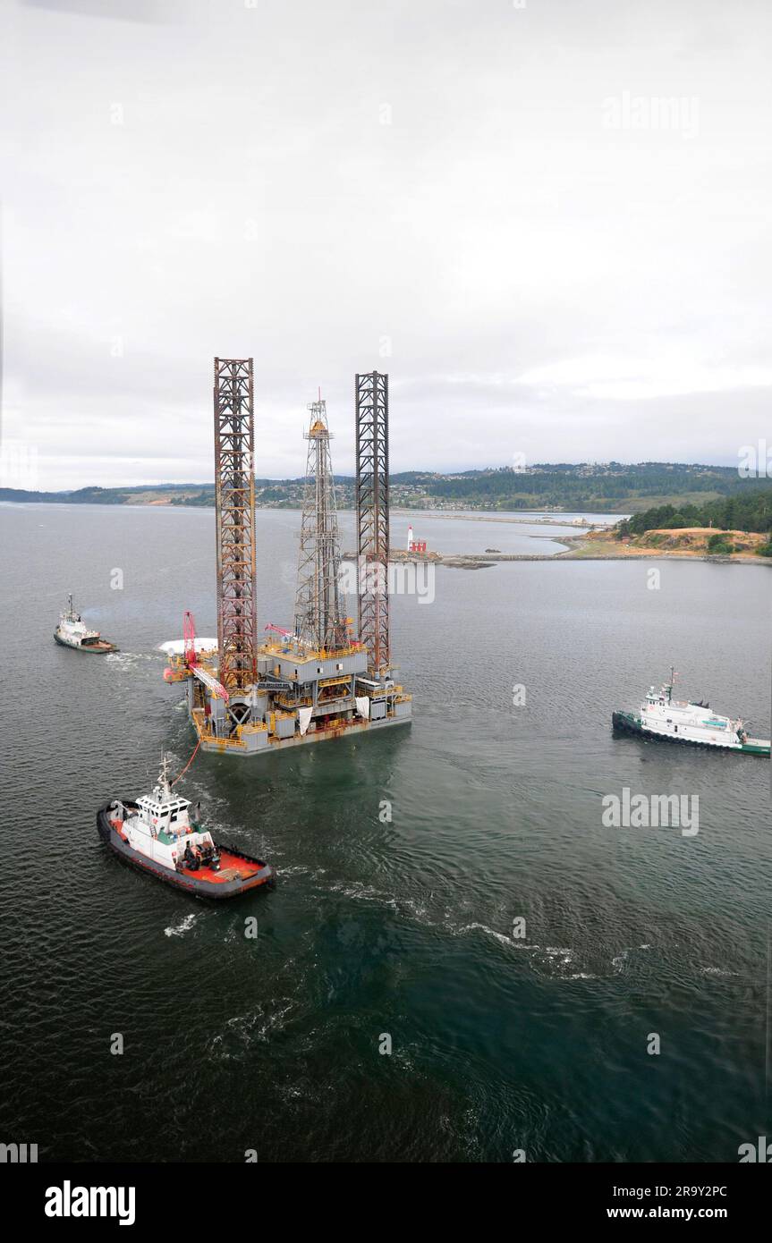 Aerial image of an oil drilling rig being towed out of port by three ...