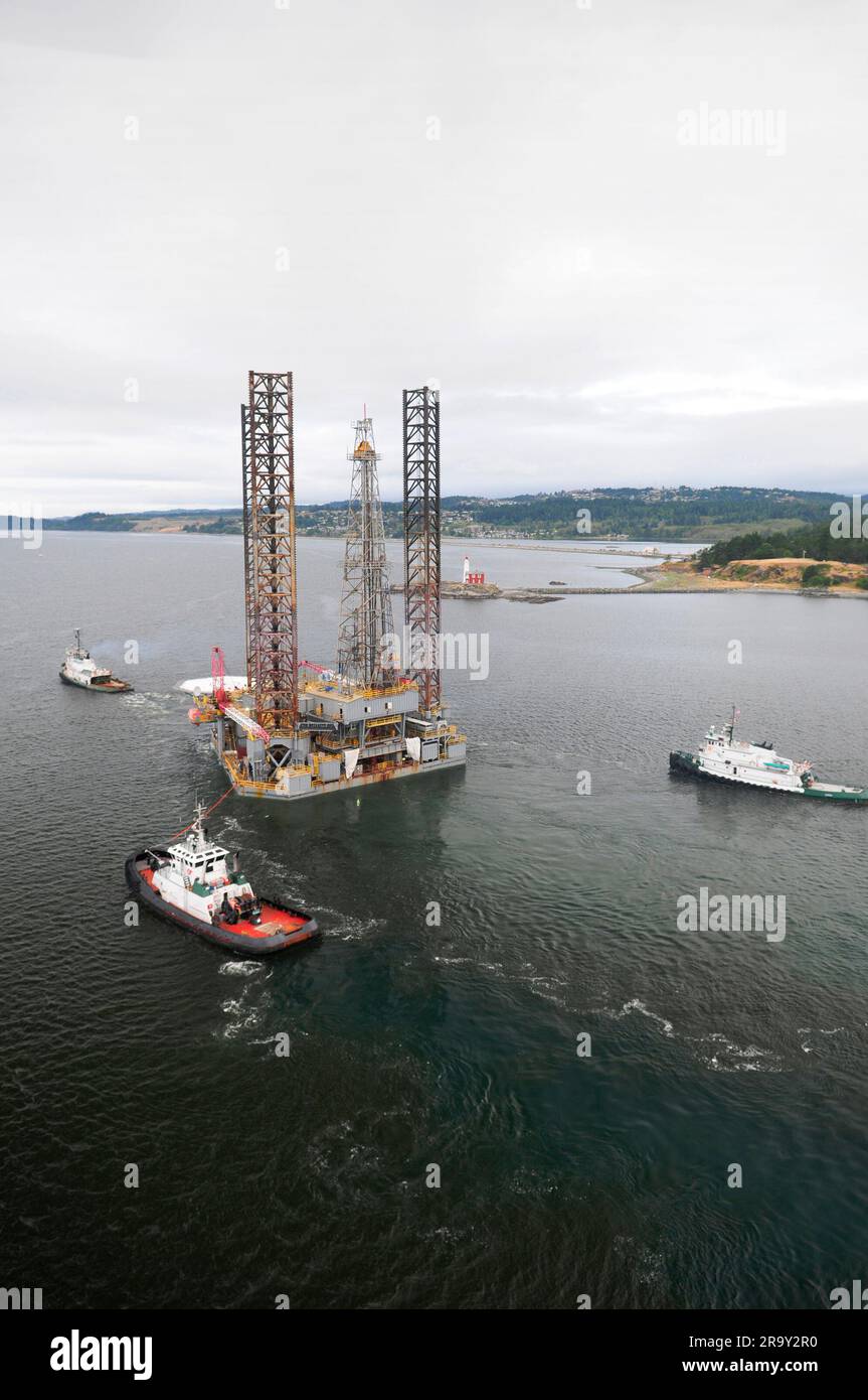 Aerial image of an oil drilling rig being towed out of port by three ...
