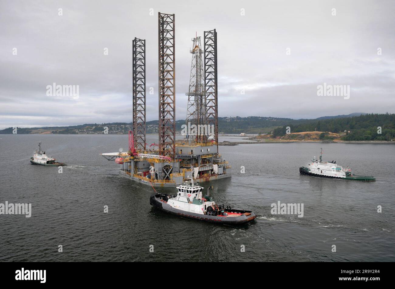 Aerial image of an oil drilling rig being towed out of port by three ...