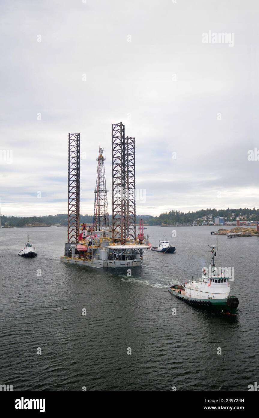 Aerial image of an oil drilling rig being towed out of port by three ...