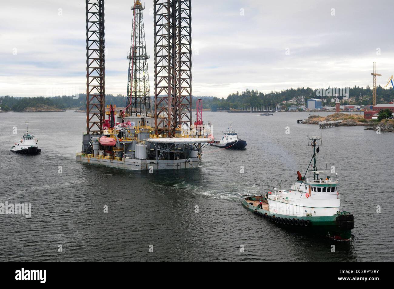 Aerial image of an oil drilling rig being towed out of port by three ...
