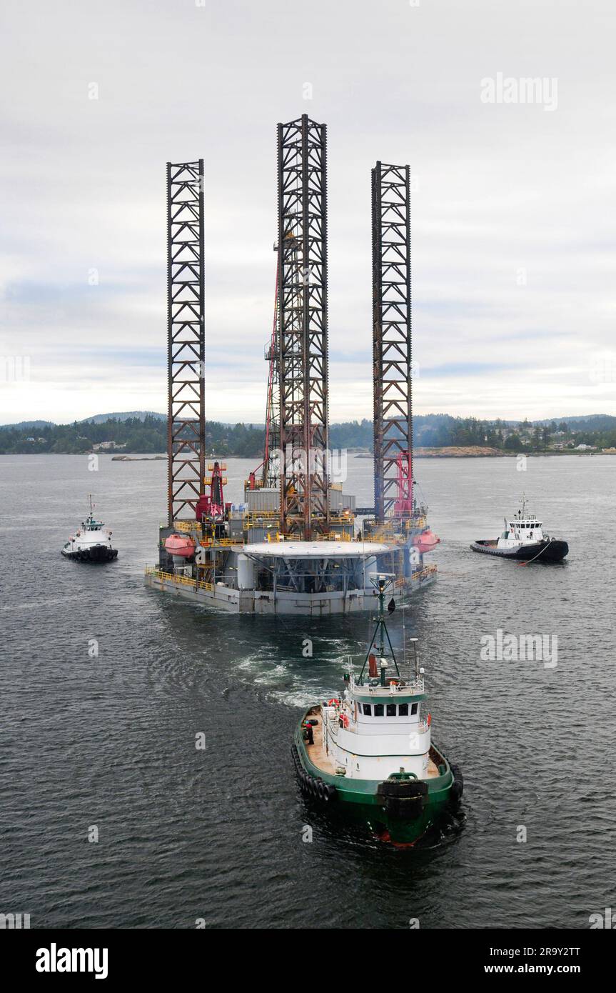 Aerial image of an oil drilling rig being towed out of port by three ...
