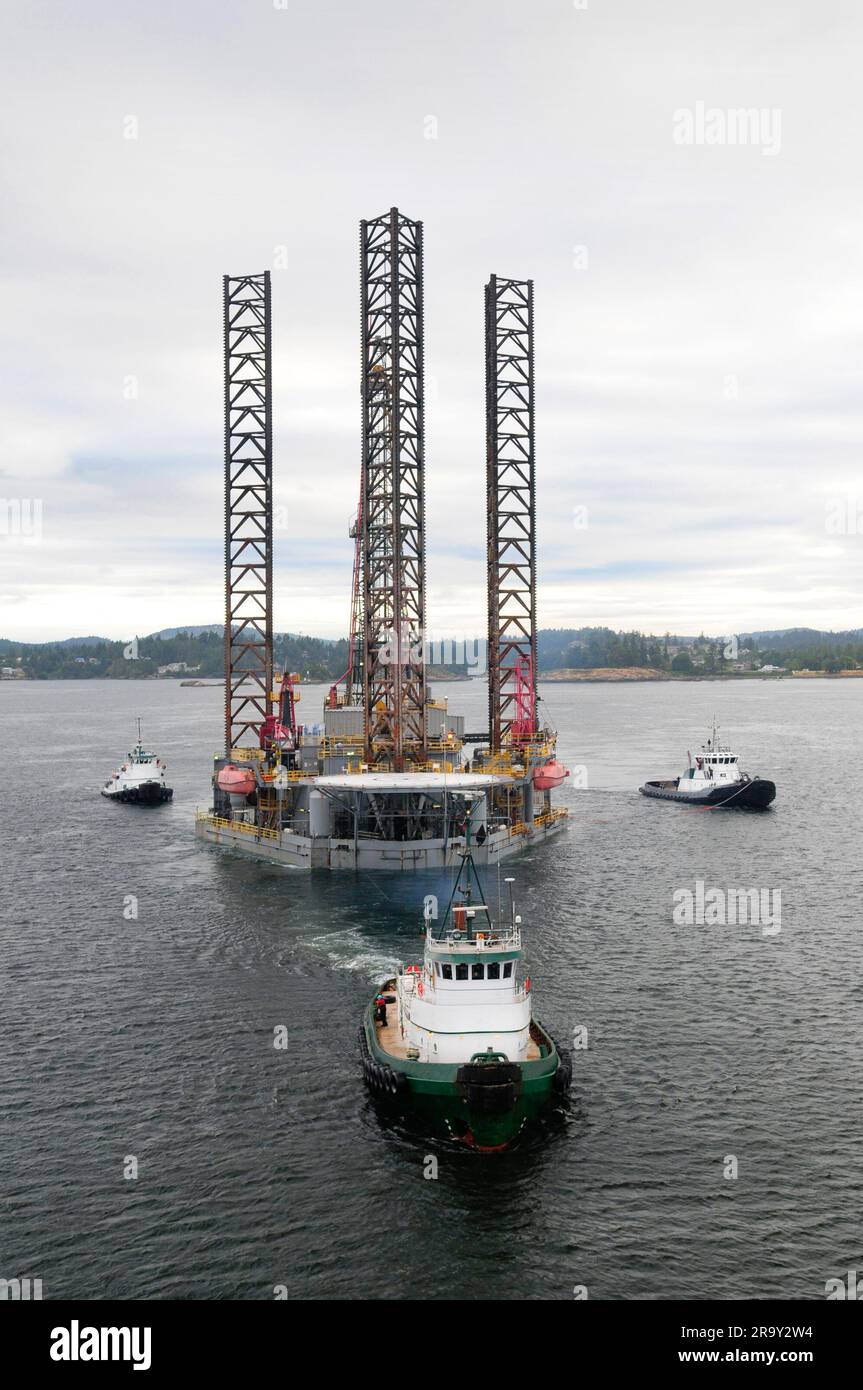 Aerial image of an oil drilling rig being towed out of port by three ...