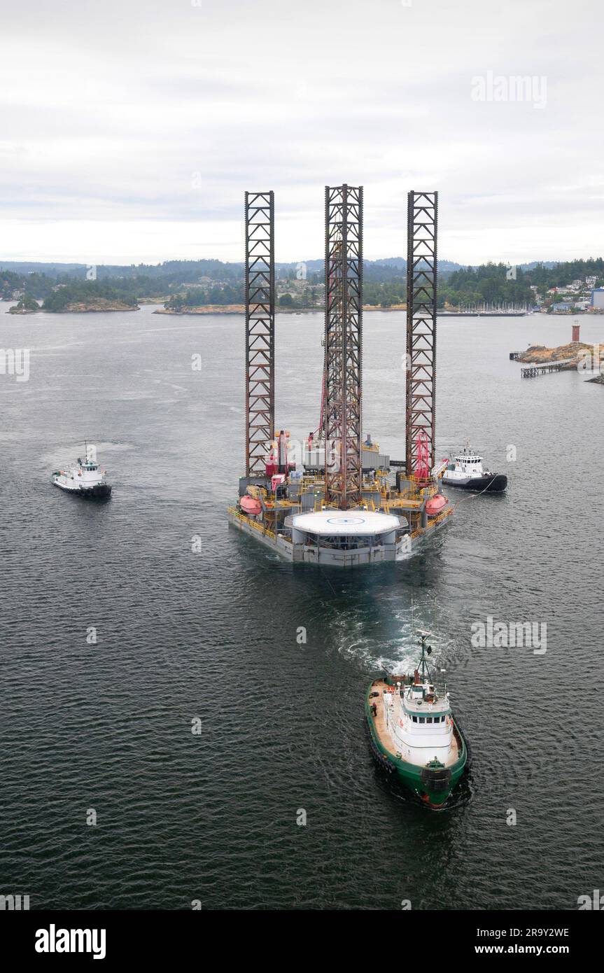 Aerial image of an oil drilling rig being towed out of port by three ...