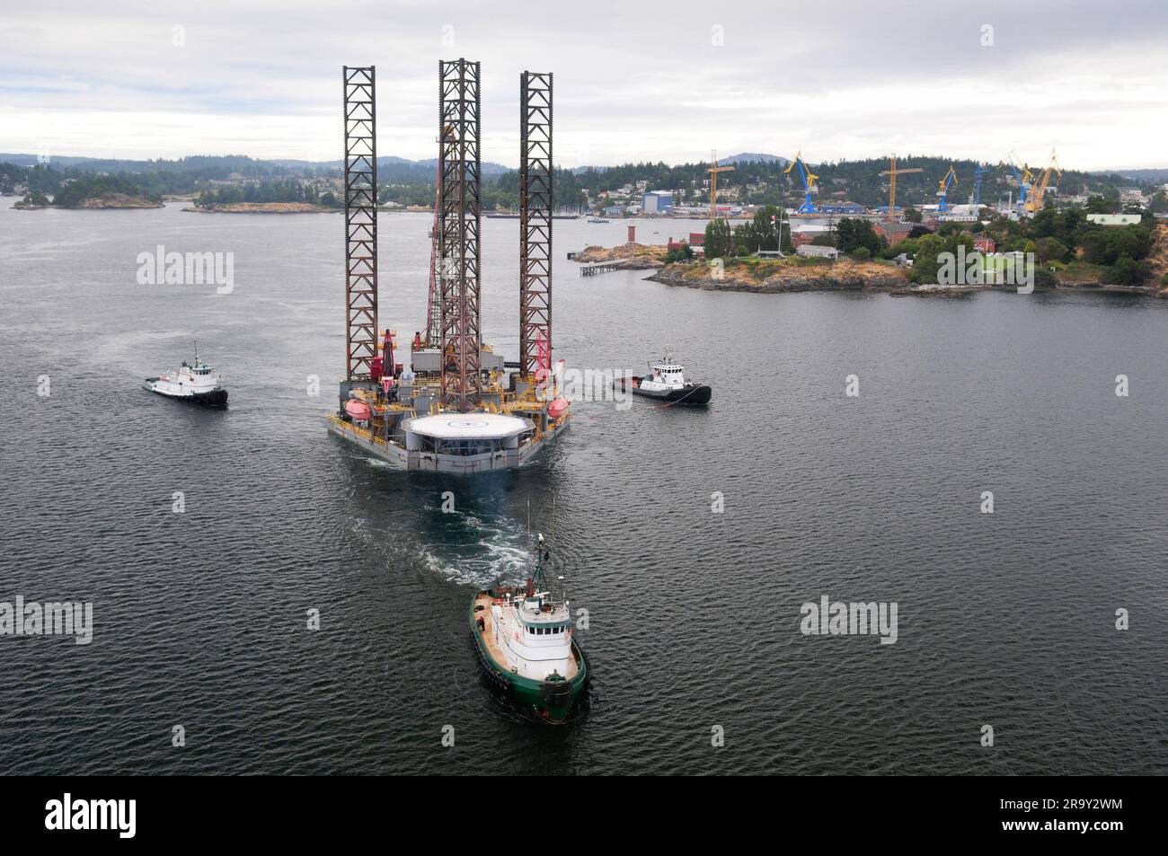 Aerial image of an oil drilling rig being towed out of port by three ...