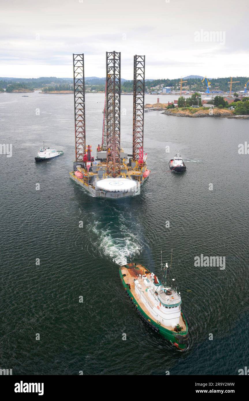 Aerial image of an oil drilling rig being towed out of port by three ...