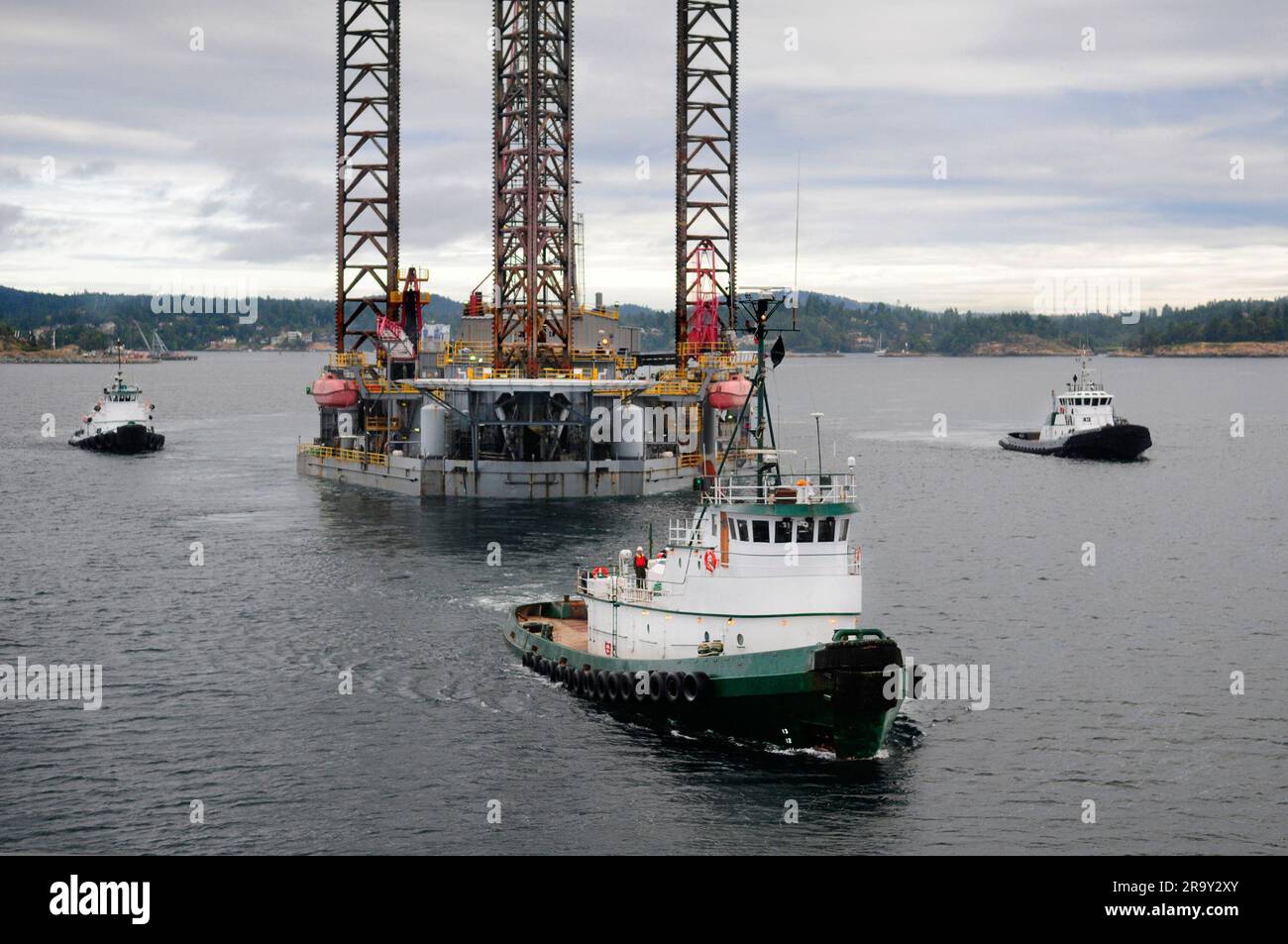 Aerial image of an oil drilling rig being towed out of port by three ...