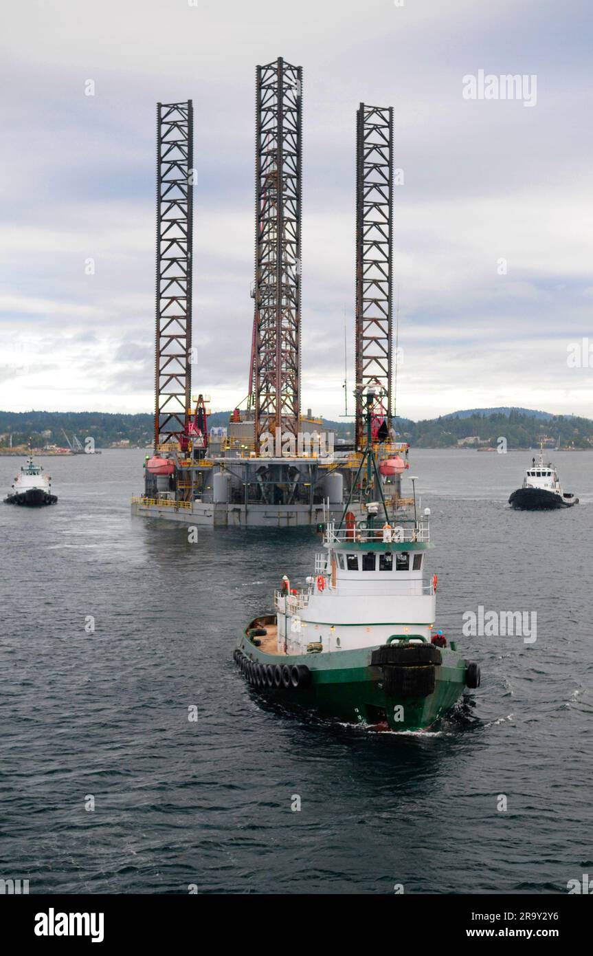 Aerial image of an oil drilling rig being towed out of port by three ...