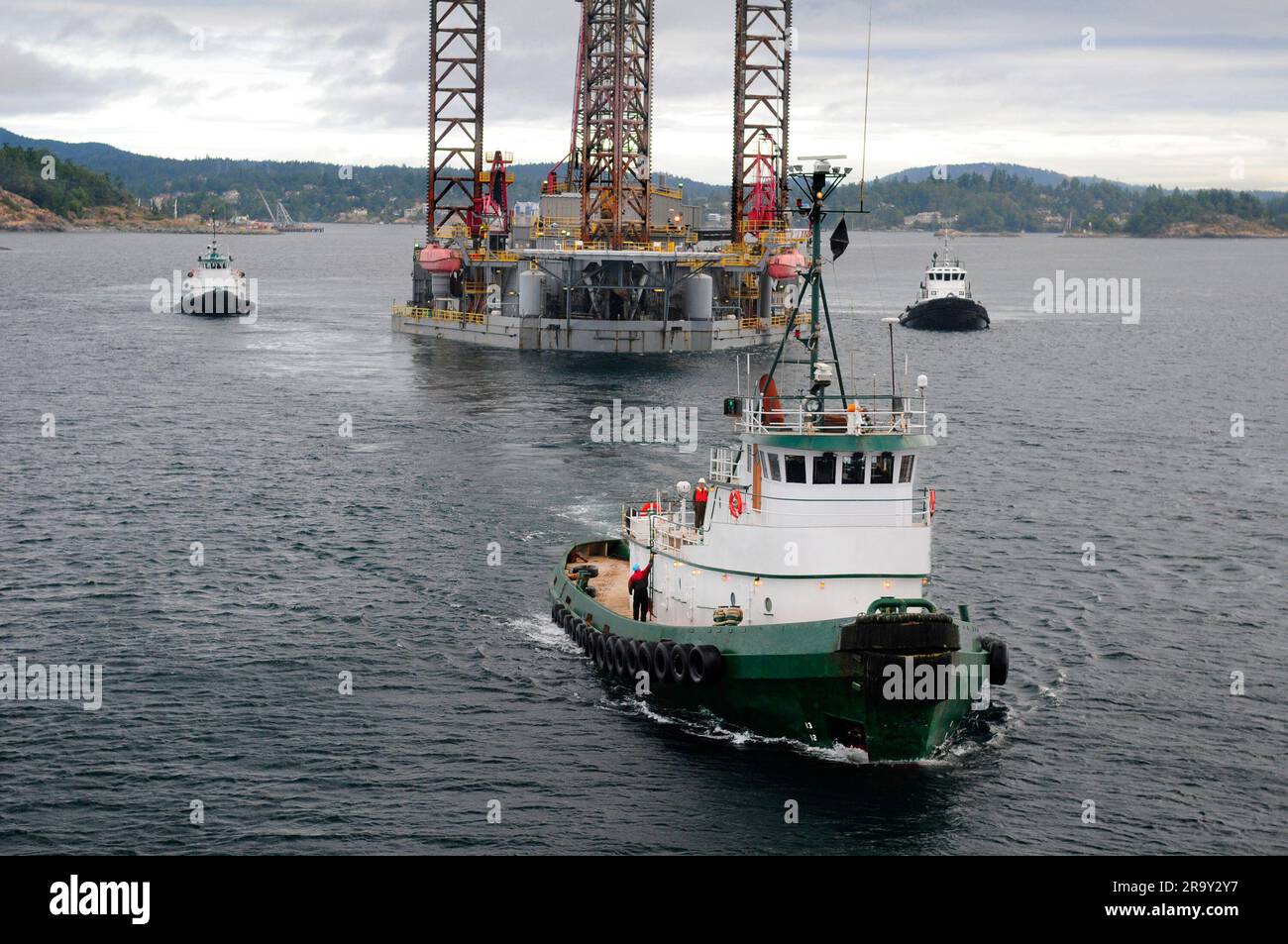 Aerial image of an oil drilling rig being towed out of port by three ...