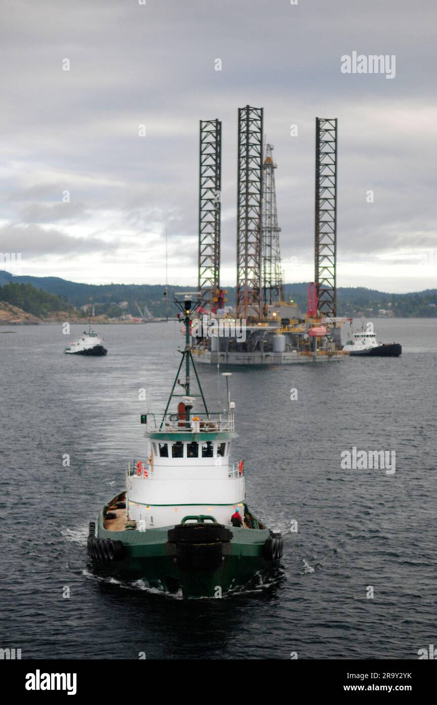 Aerial image of an oil drilling rig being towed out of port by three ...