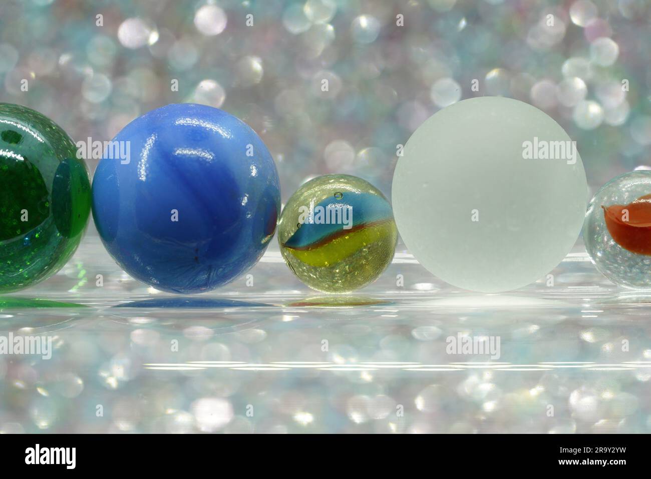 Glass balls and colorful marbles against a light blurred background ...