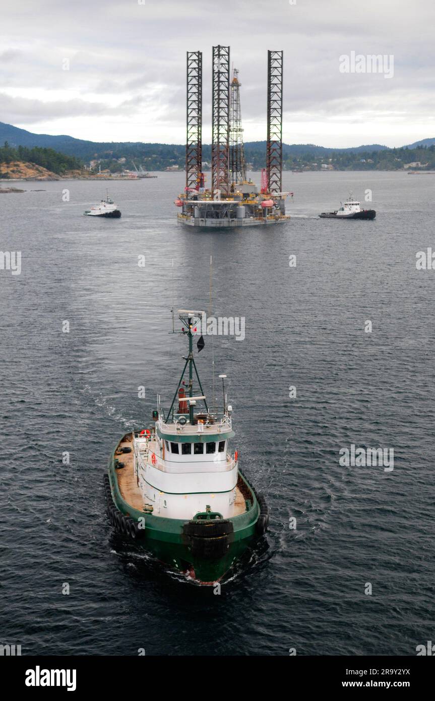 Aerial image of an oil drilling rig being towed out of port by three ...