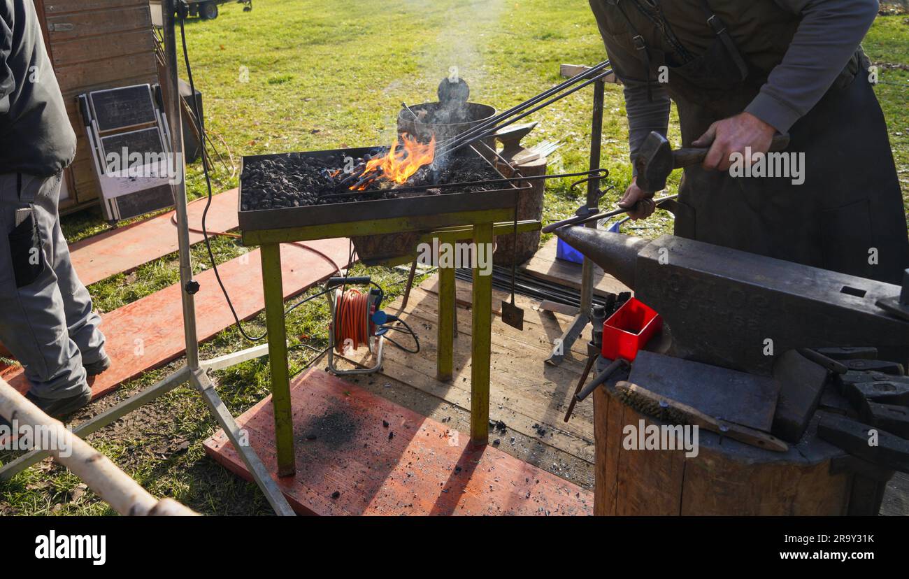 Blacksmith with red-hot iron and open charcoal fire at work Stock Photo ...