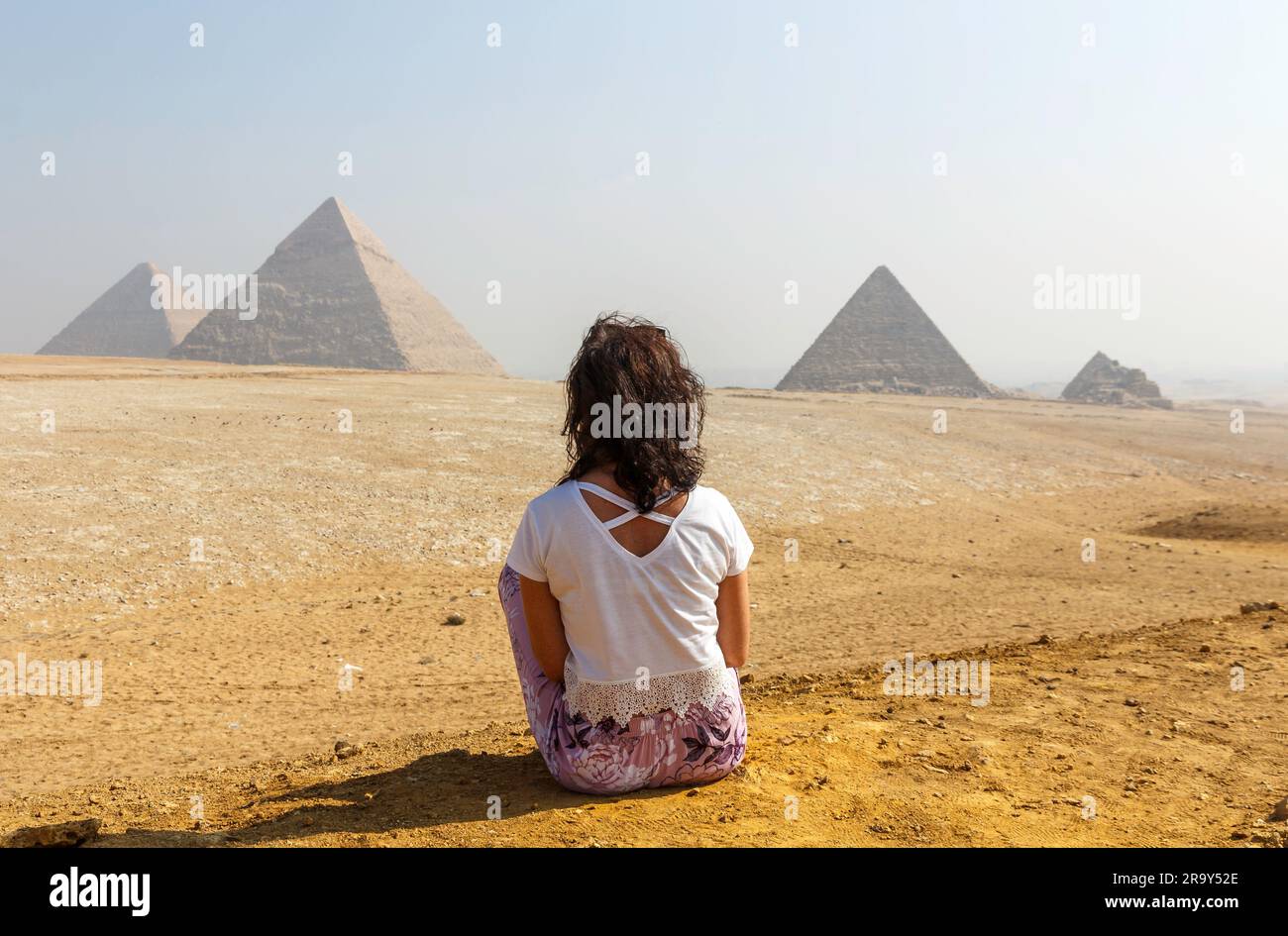 A rear view of a young female sitting on the sand looking at the famous ...