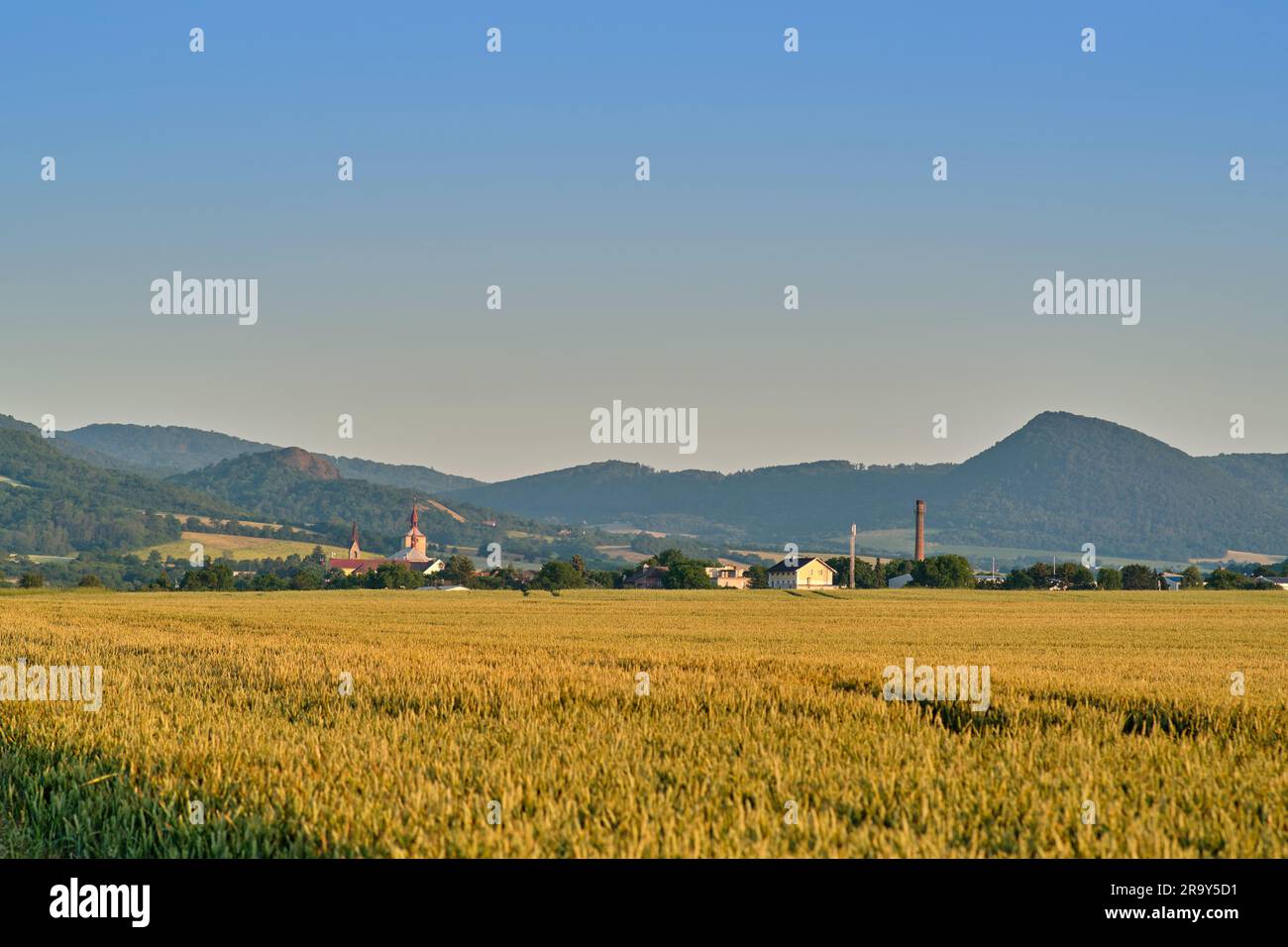 Rural village houses under range of mountains with forest and ...