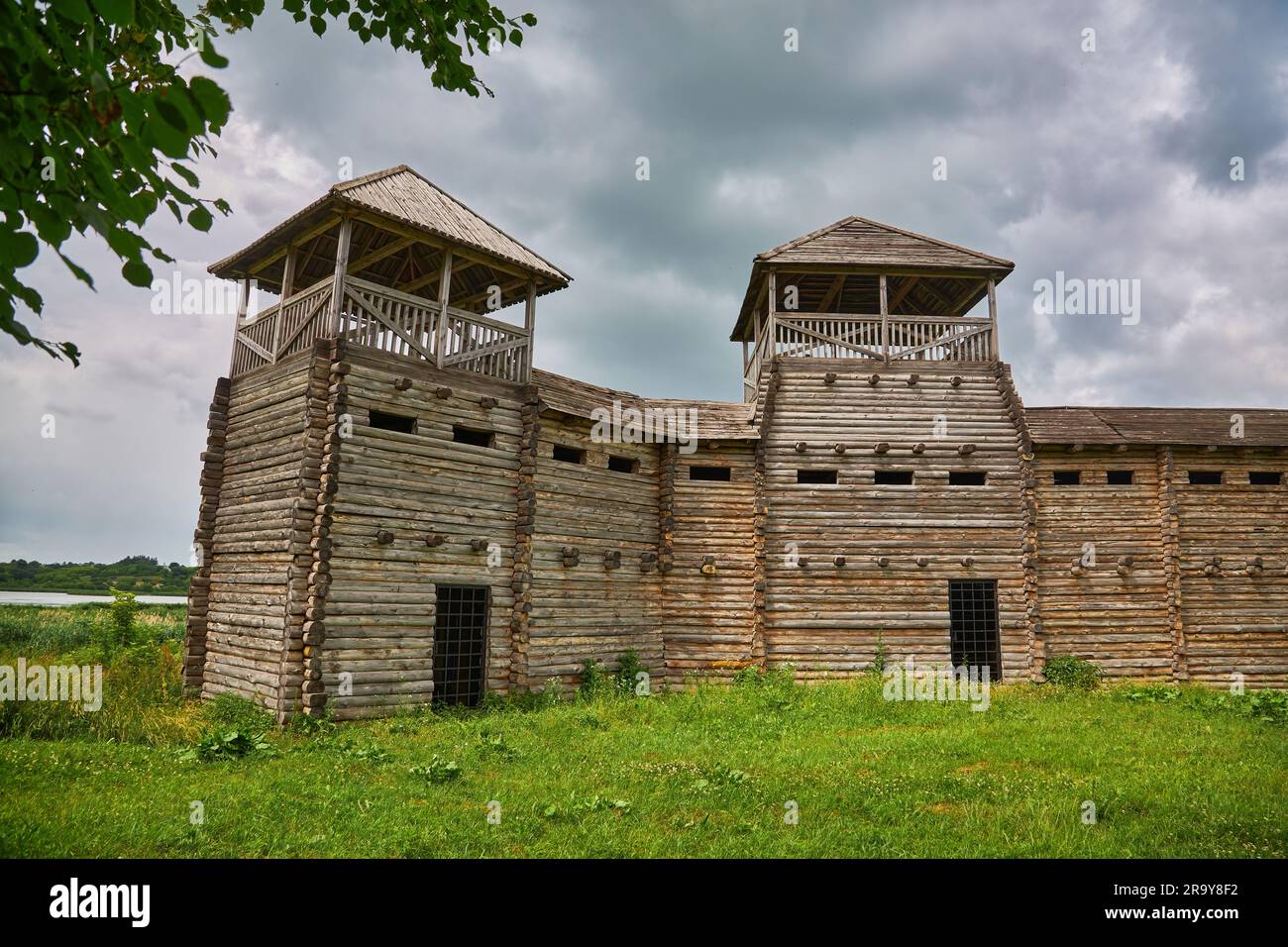 An old wooden fortress surrounded by a fence with sharp peaks on a ...