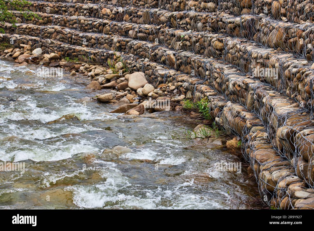Strengthening the banks of the mountain river, mesh and stones ...