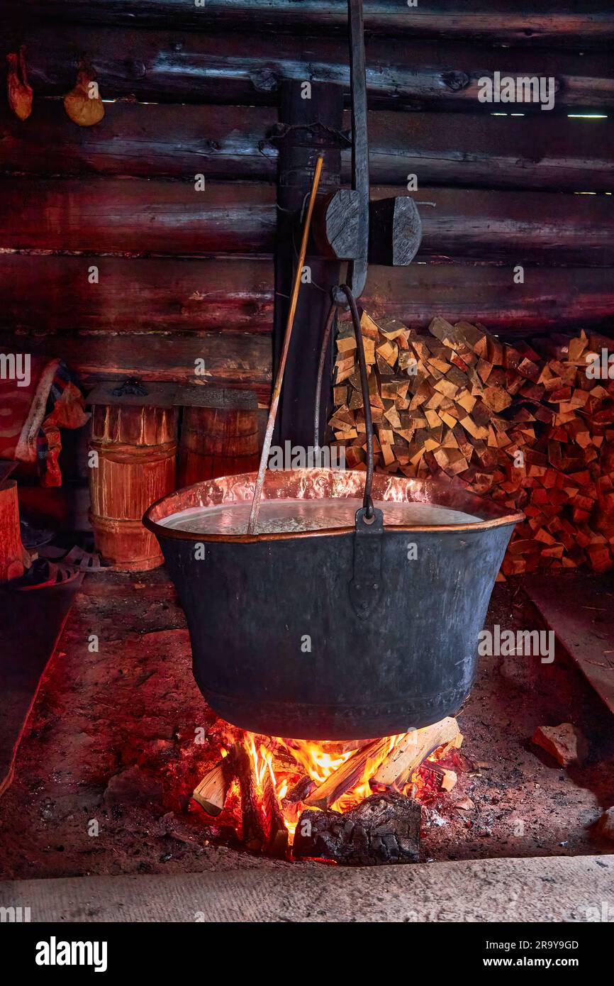 A large vat in which cheese is cooked over an open fire. The black ...