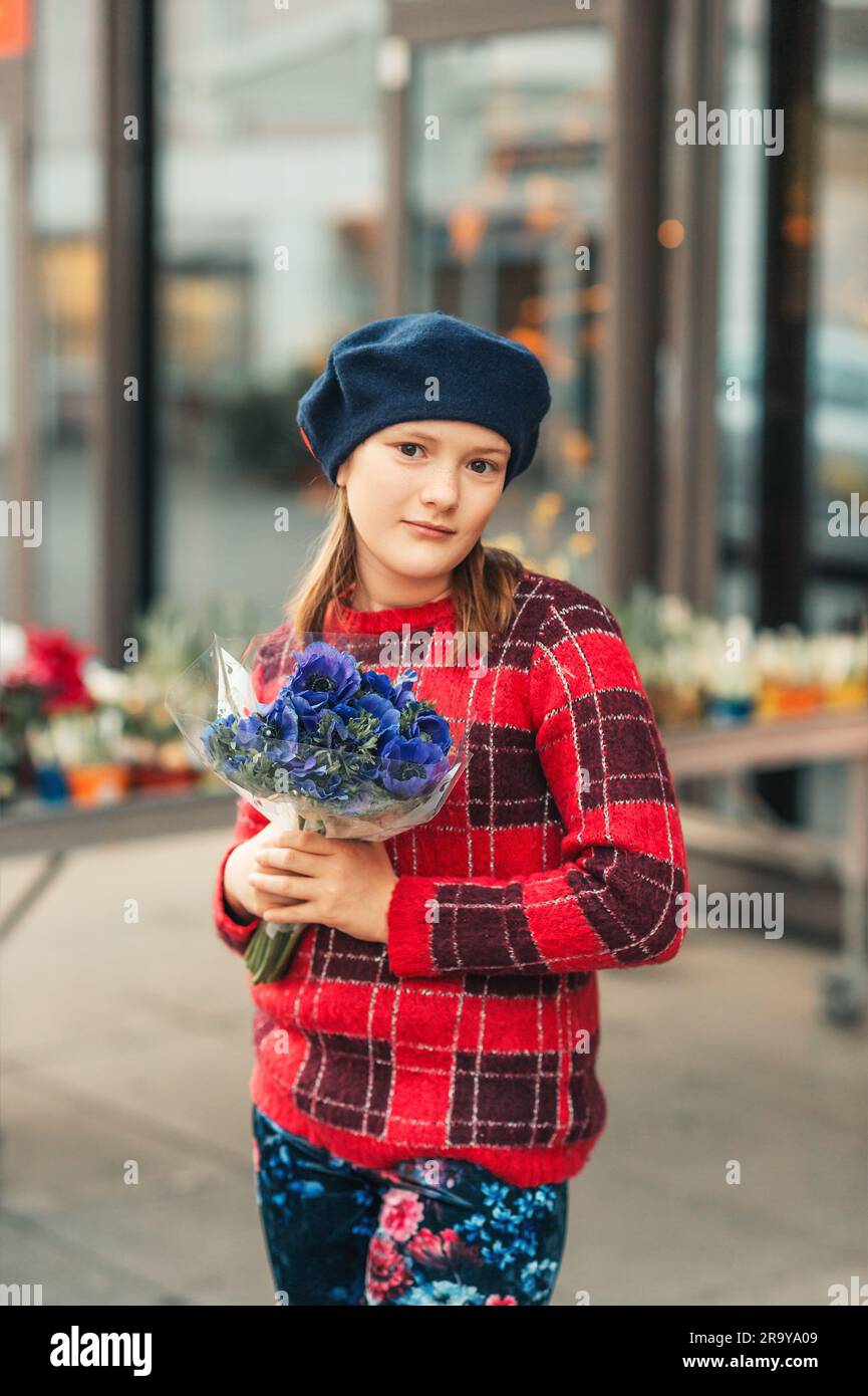 Outdoor portrait of cute little girl holding purple anemone flowers ...