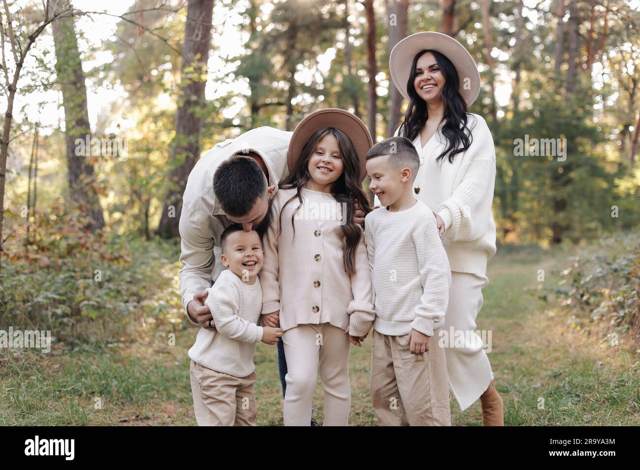 Young mother, father with daughter and sons are walking, having fun in autumn forest. Family ...