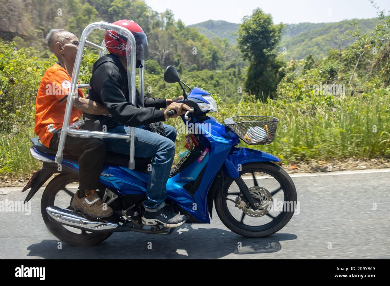 THAILAND, MAY 19 2023, Men ride a motorcycle with a load on a mountain ...