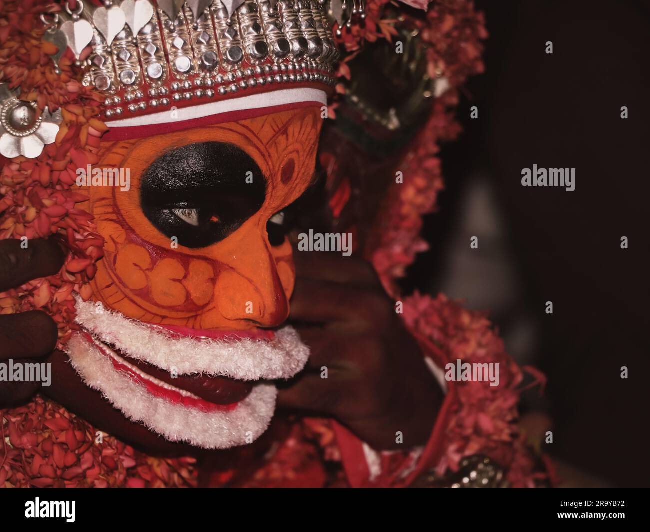 a closeup headshot portrait of a theyyam artist decorated with ...