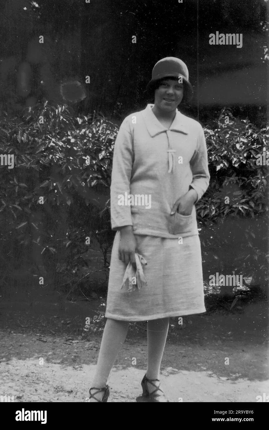 A posed portrait of a lady in a garden. Photo from a family album of ...