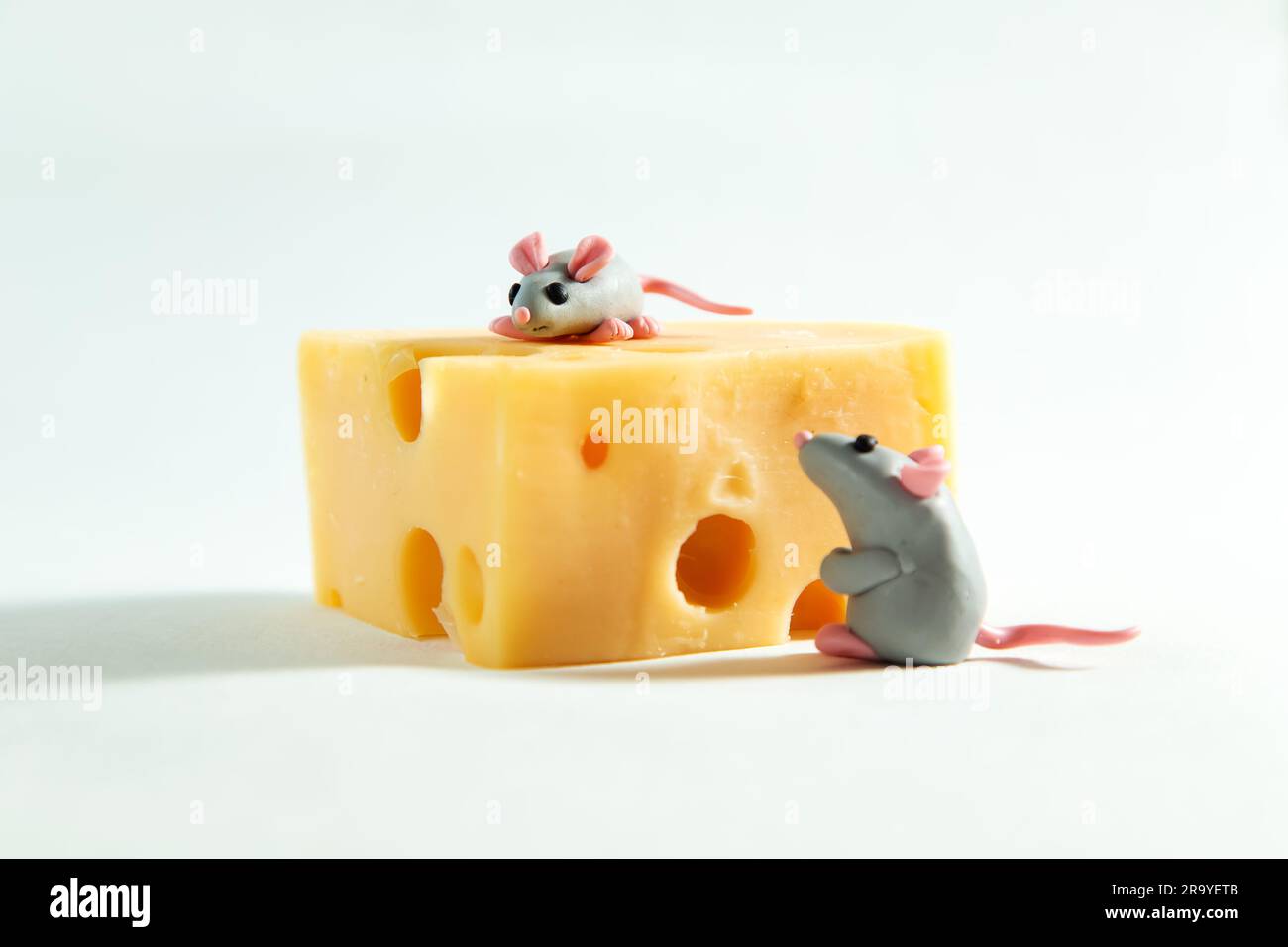 Little plasticine mice and a piece of cheese with holes. White ...