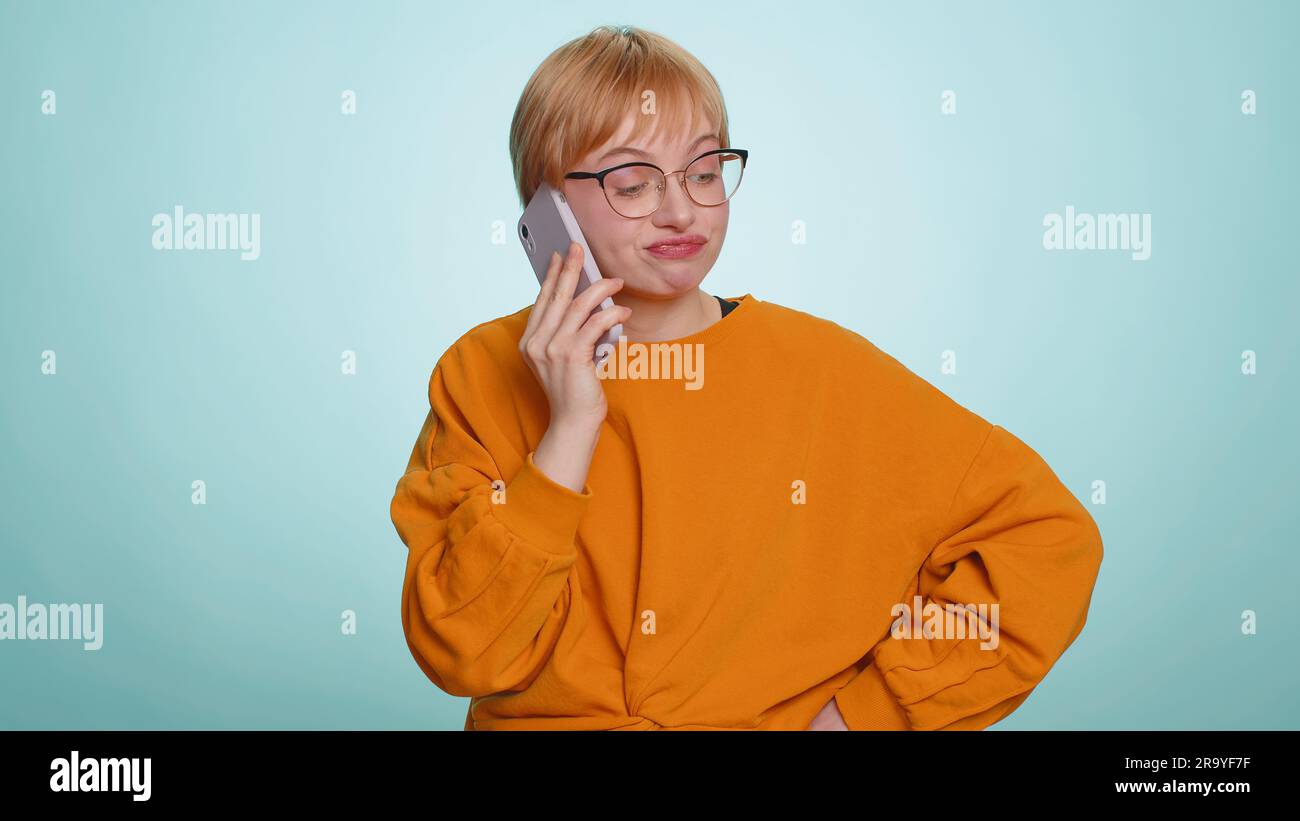 Tired sleepy young woman in glasses talking on mobile phone with friend ...