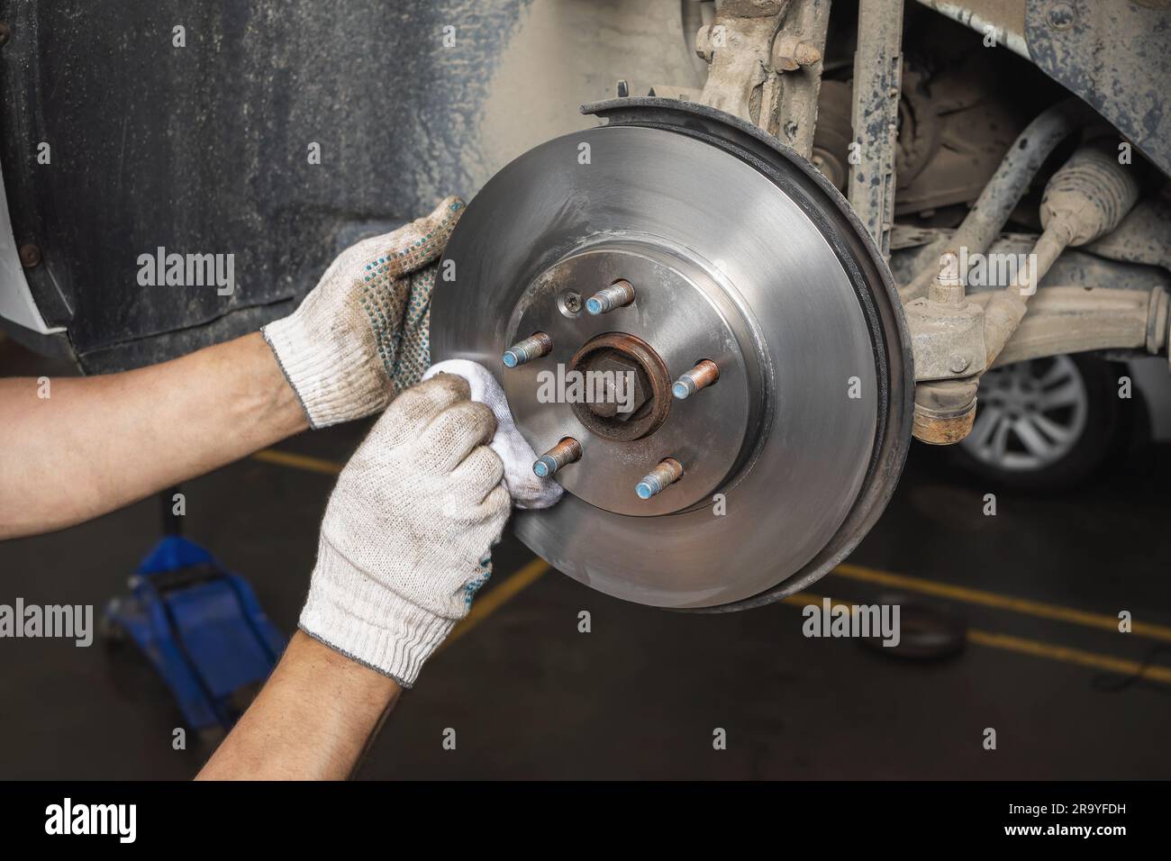 An auto mechanic removes dirt and grease residue from a newly installed ...