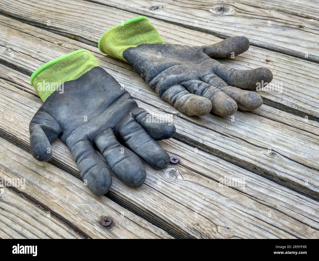 a pair of well used, dirty bamboo garden gloves on a wooden rustic deck ...