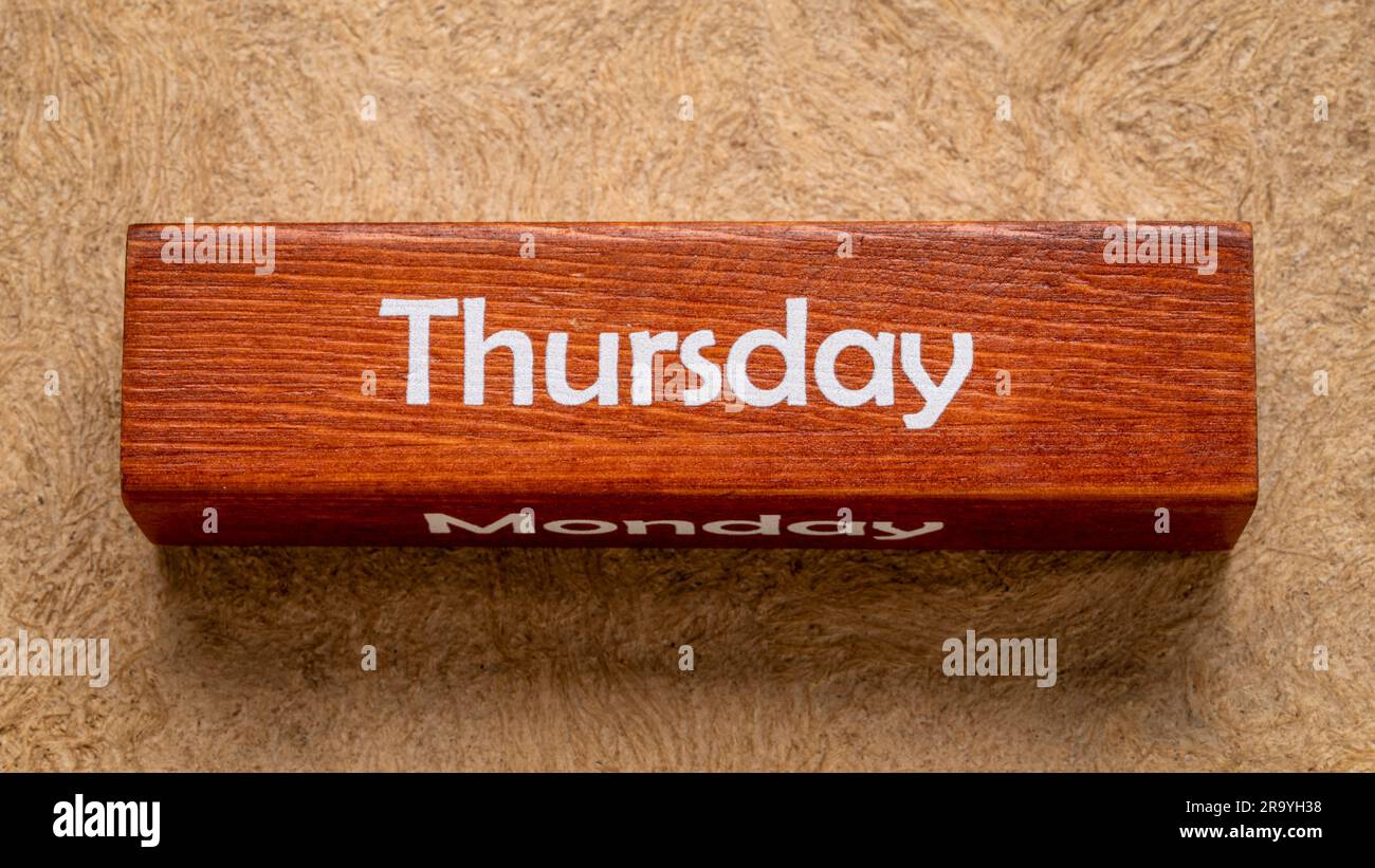 Thursday and Monday text on wooden block against handmade bark paper in ...